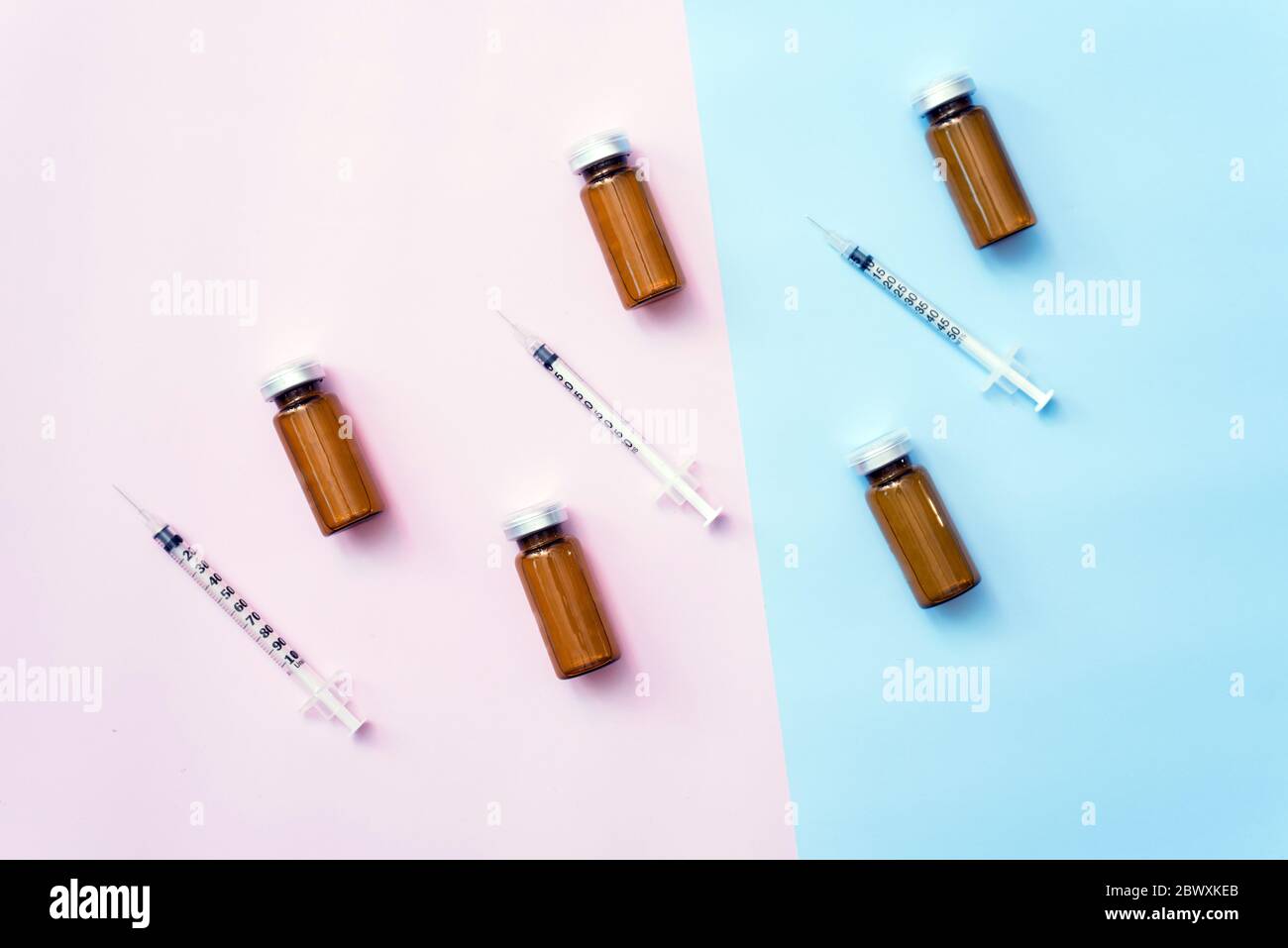 Syringe with filler for cosmetology and ampules on blue and pink ...