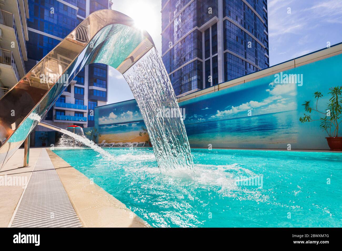Outdoor swimming pool with cascade on cityscape background Stock Photo ...