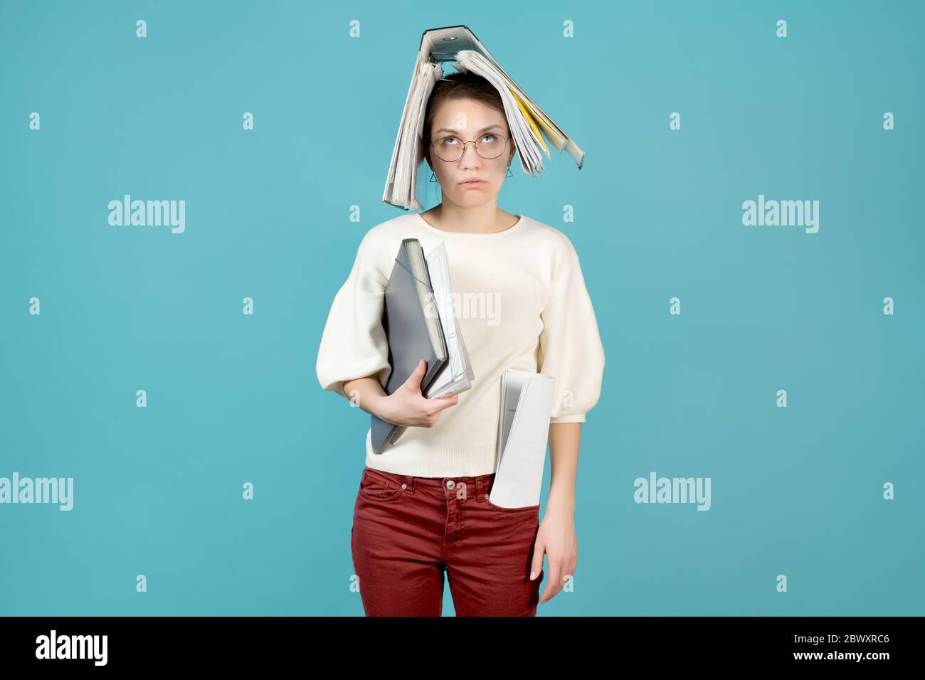 Overloaded office worker with a folder of documents on her head. Holds ...