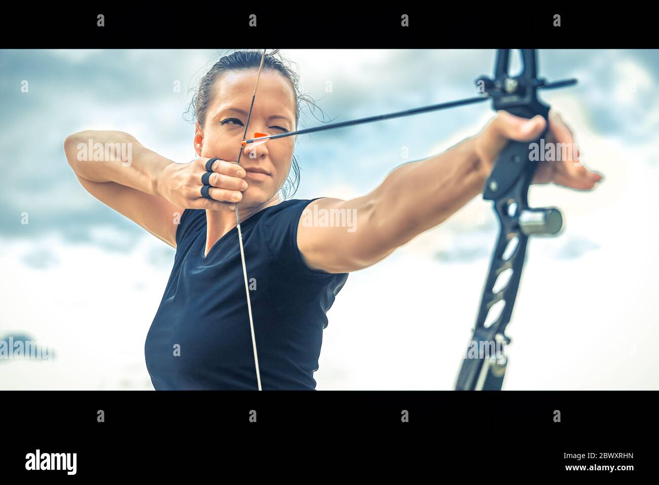 attractive woman on archery, focuses eye target for arrow from bow ...