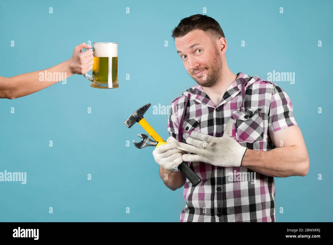 A dirty hard worker with tools in his hands pulls a protective glove ...