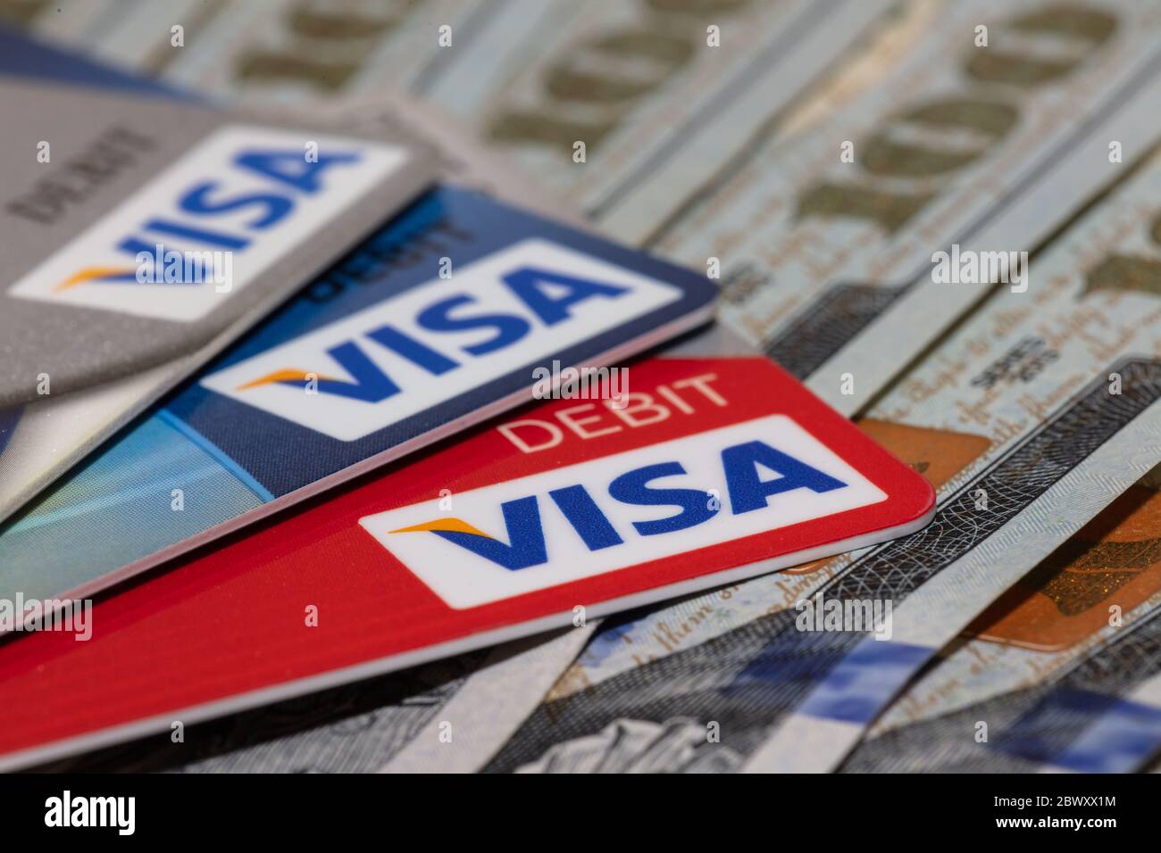 Red, blue, and silver Visa debit cards on hundred dollar bills. Some ...