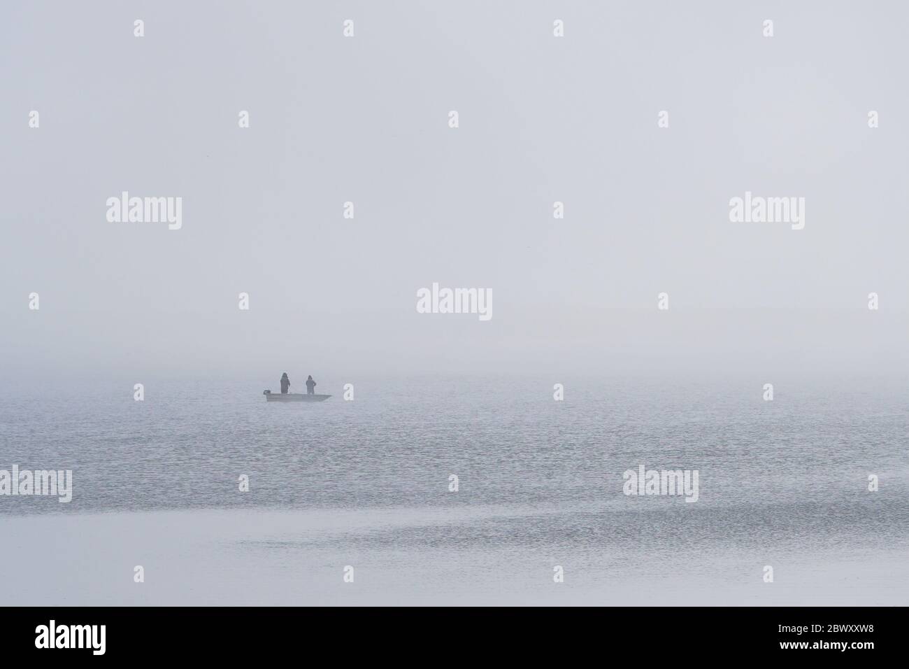 view of the lake and a boat with anglers in the fog Stock Photo - Alamy