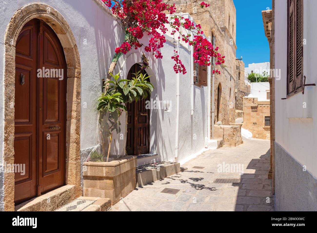 Greek street with spring flowers on Rhodes island. Lindos village ...