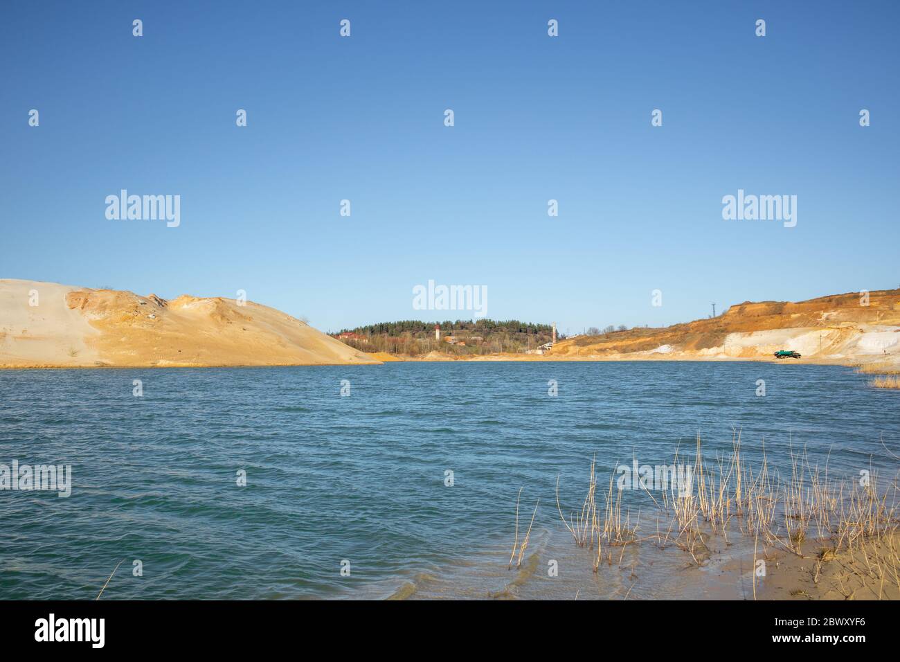 Small waves on blue water and a sandy beach. Pond on a sand quarry ...