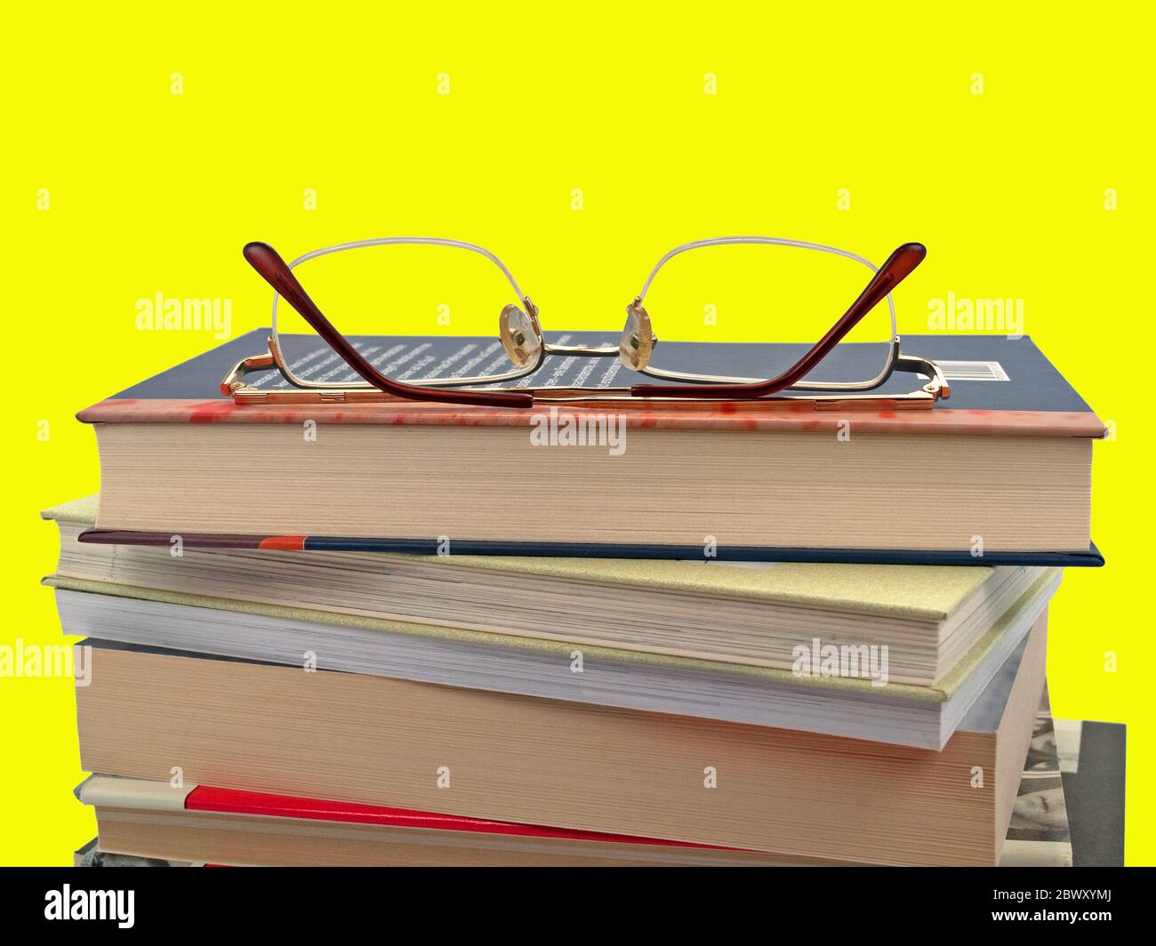Stacked books against yellow background Stock Photo - Alamy