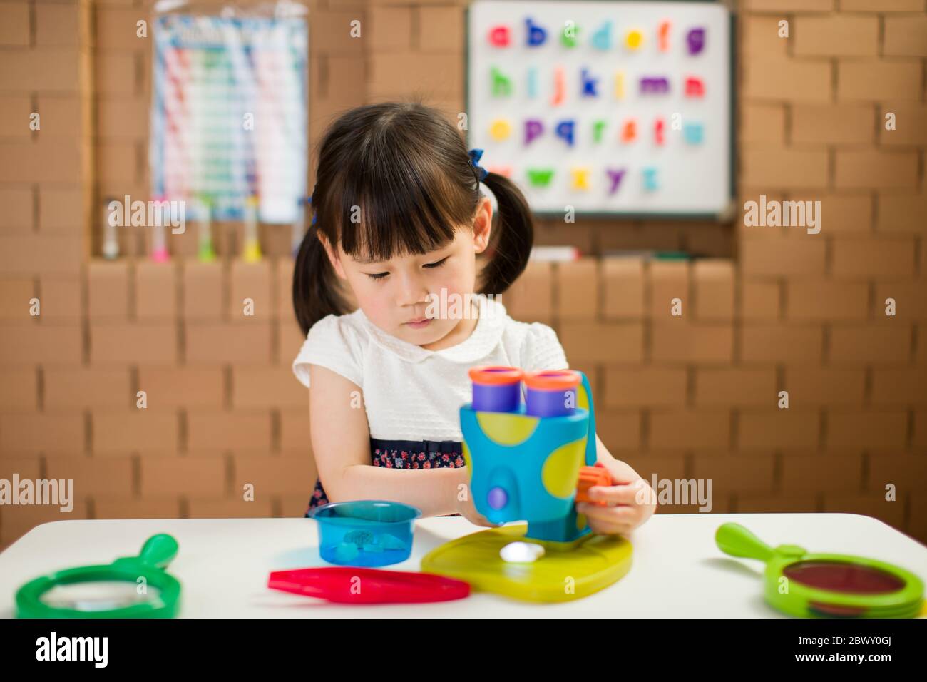 toddler girl play microscope for homeschooling Stock Photo - Alamy