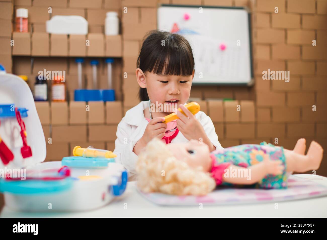 toddler girl pretend play doctor role at home against white background ...