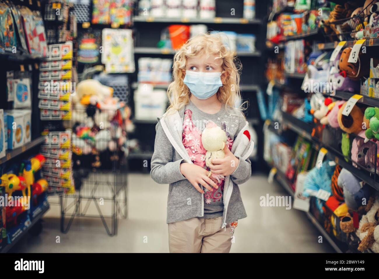 A new normal. Caucasian blonde girl in sanitary face mask shopping at ...