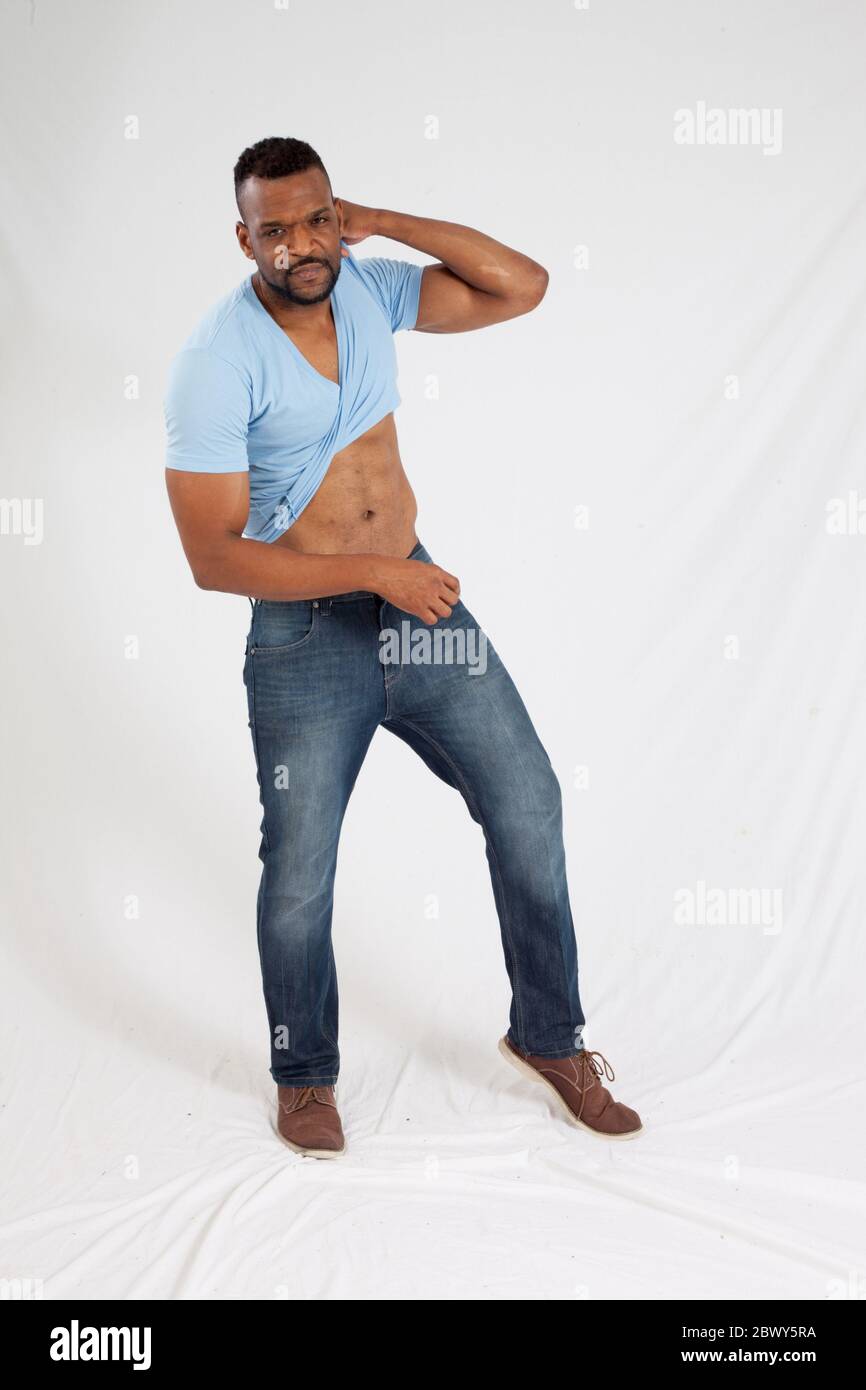 Handsome Black man lifting his blue shirt to show his abdomen Stock ...