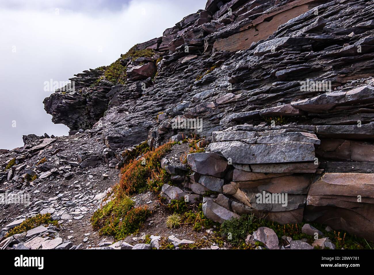 jagged rocky mountain side close up texture with moss and clouds in the ...