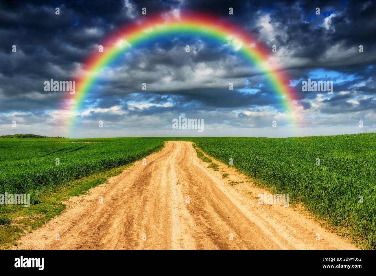 Rainbow over field road Stock Photo - Alamy
