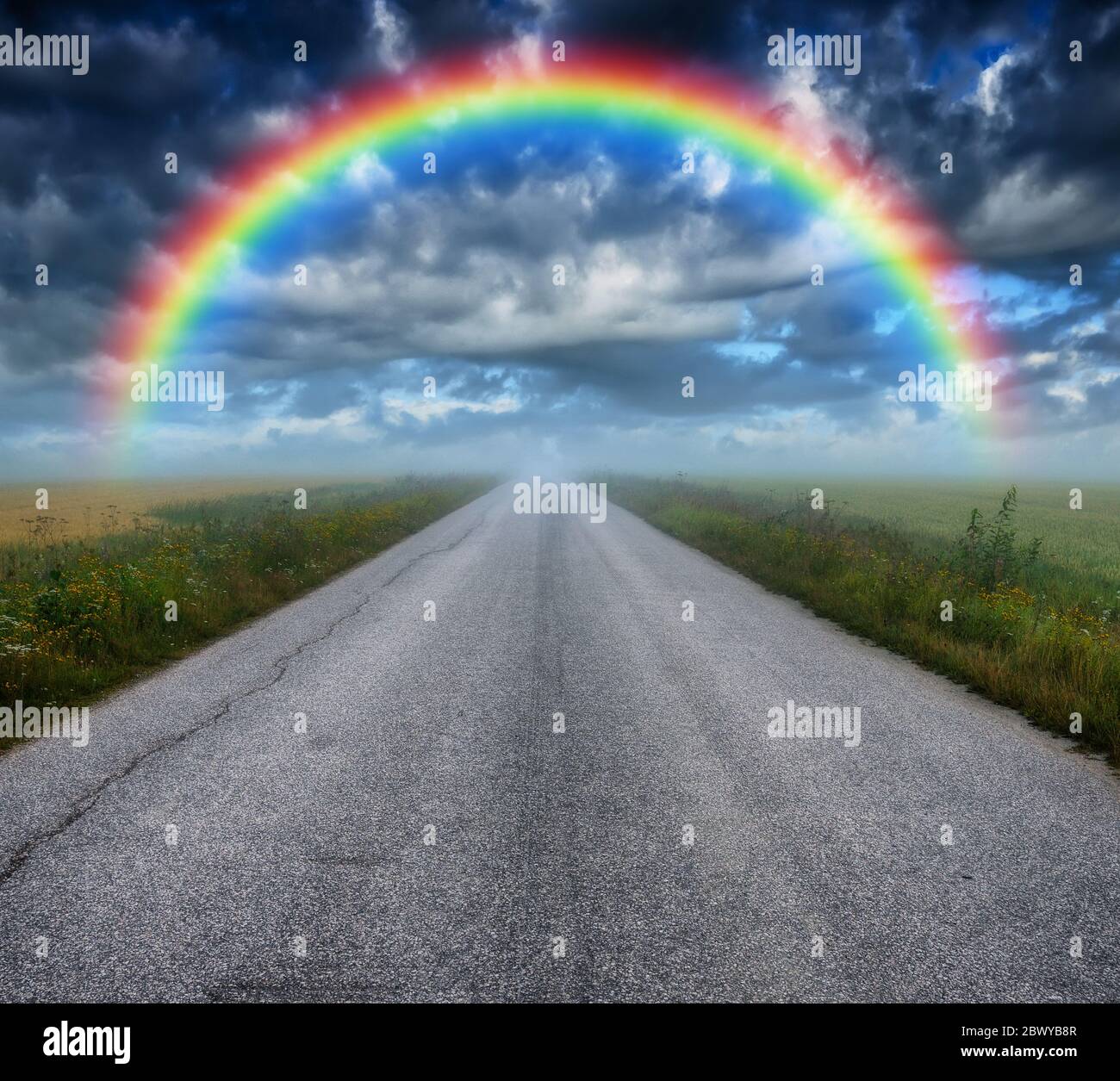 Rainbow over field road Stock Photo - Alamy