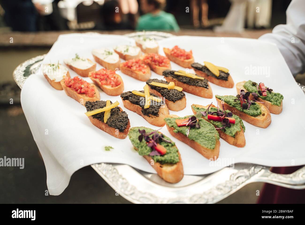 Man carrying tray with various mini sandwiches. Small tasty snacks ...