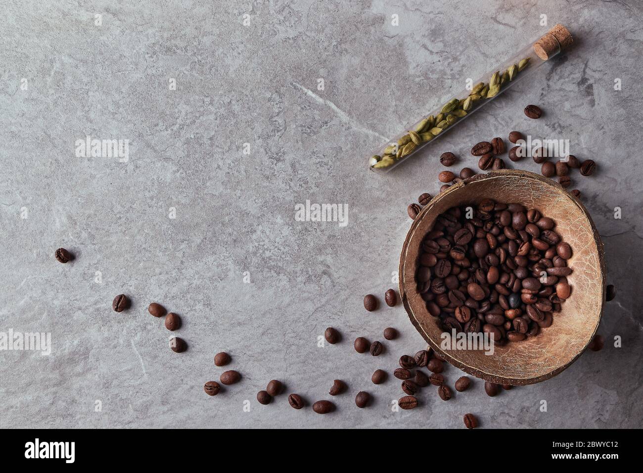 Overhead view of roasted coffee beans in coconut shell on rustic wooden ...