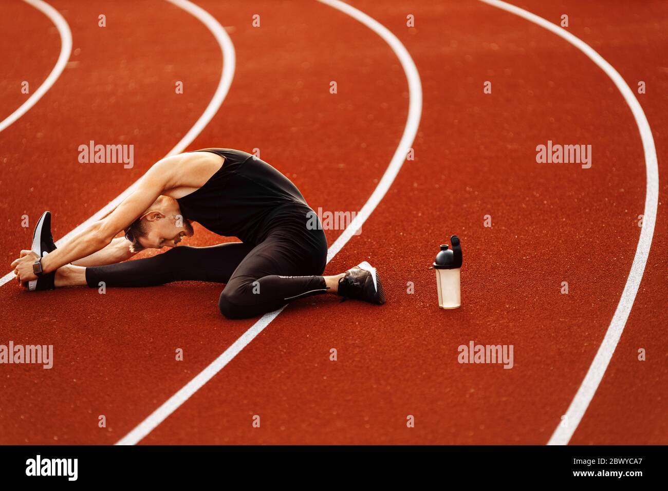 Young athlete resting after running in the stadium at summer Stock ...