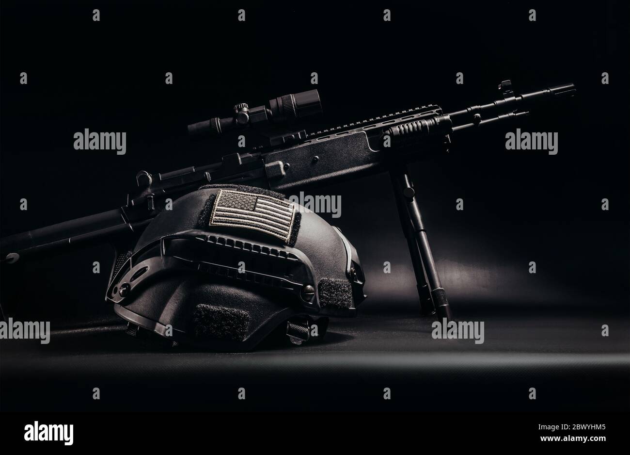 Photo of a black sniper rifle standing on table with soldier helmet ...
