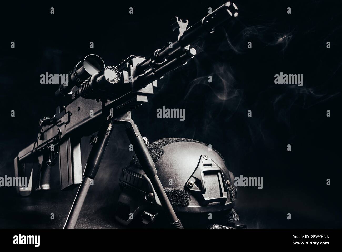 Photo of a black sniper rifle standing on table with soldier helmet on ...