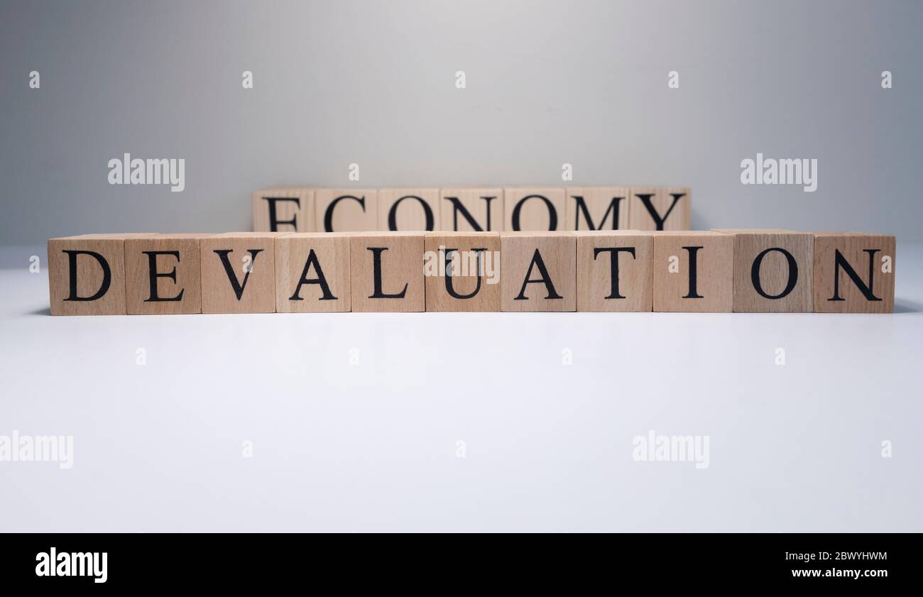 The word devaluation from wooden cubes is in the white background Stock ...