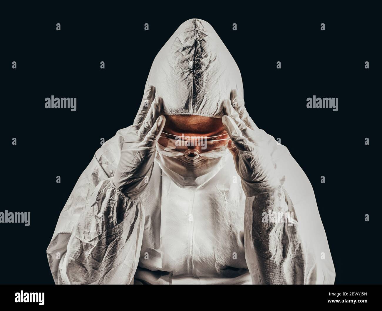 Photo of sad and tired medic in protective lab suit, respirator, gloves ...