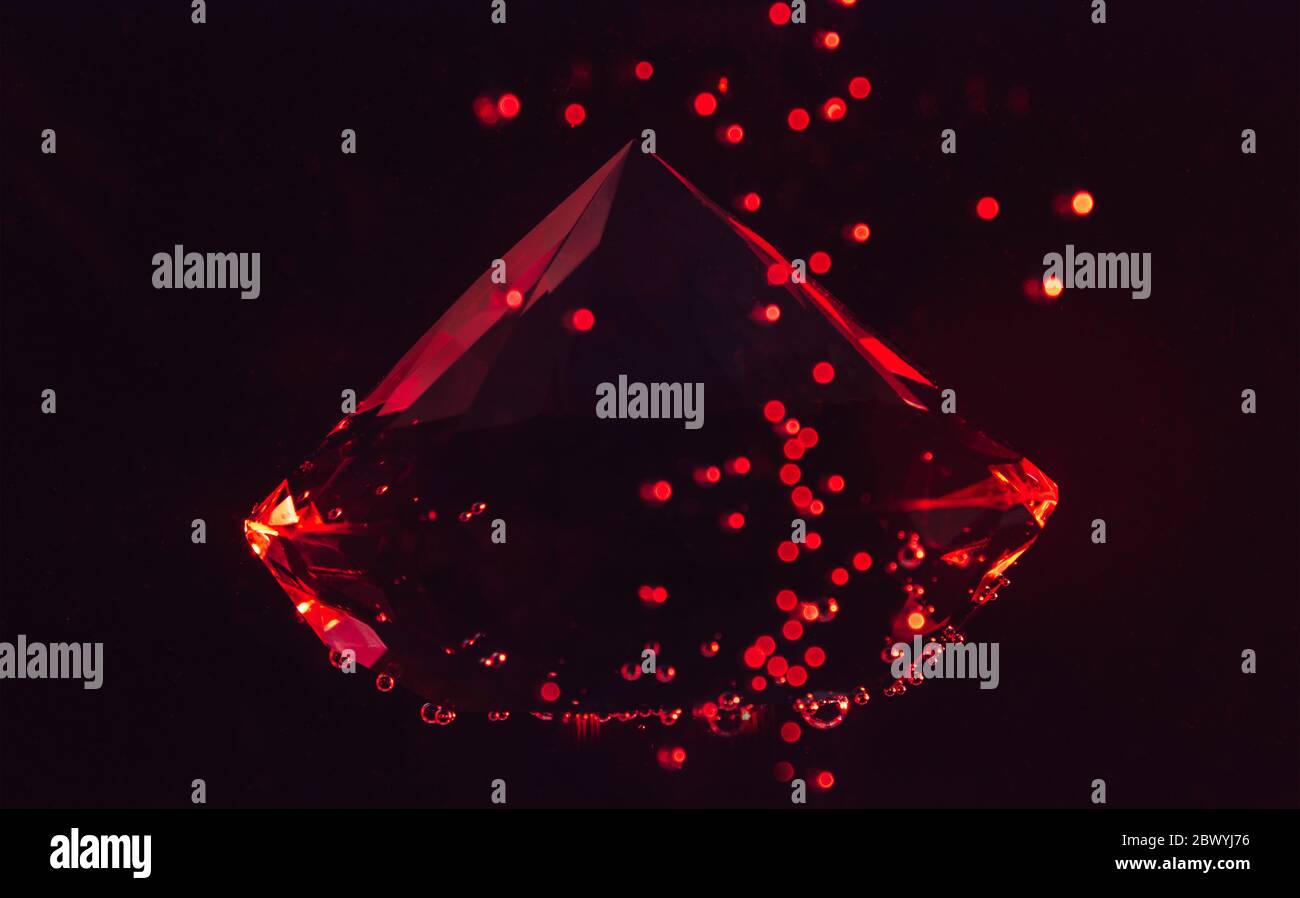 Photo of a shiny red ruby in water with air bubbles on dark red ...