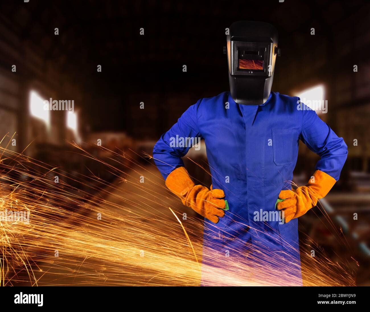Photo of a welder worker in protective robe, helmet and gloves standing ...