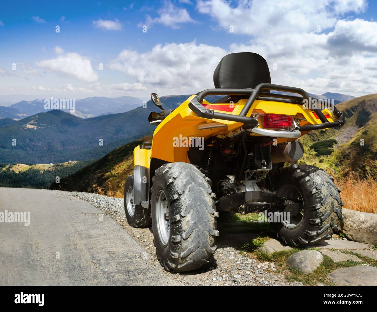 Photo of a yellow offroad touring atv vehicle standing on a mountain ...