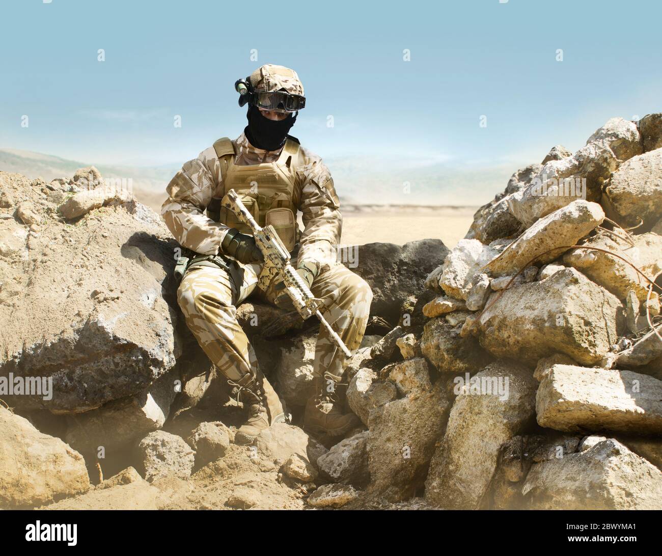 Photo of a fully equipped military soldier with rifle sitting in desert ...