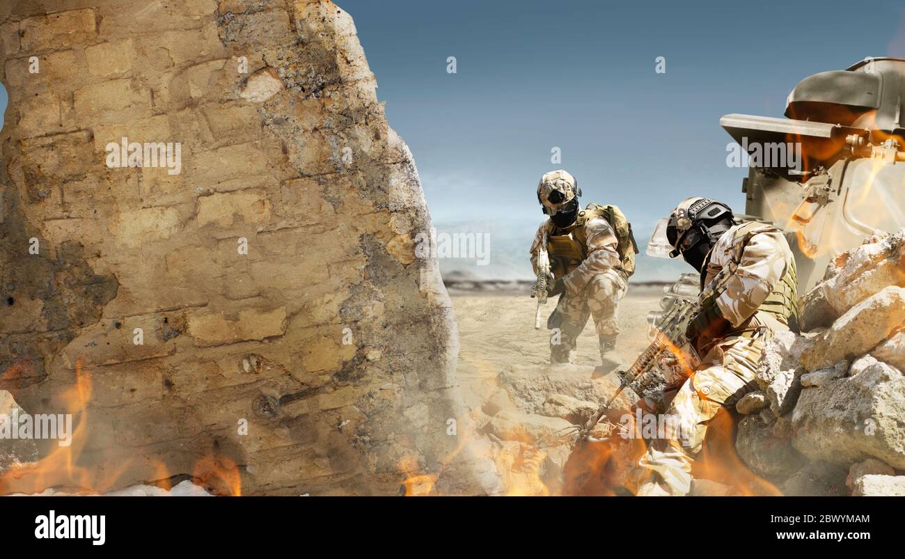Photo of a fully equipped desert soldiers with rifle taking cover in ...