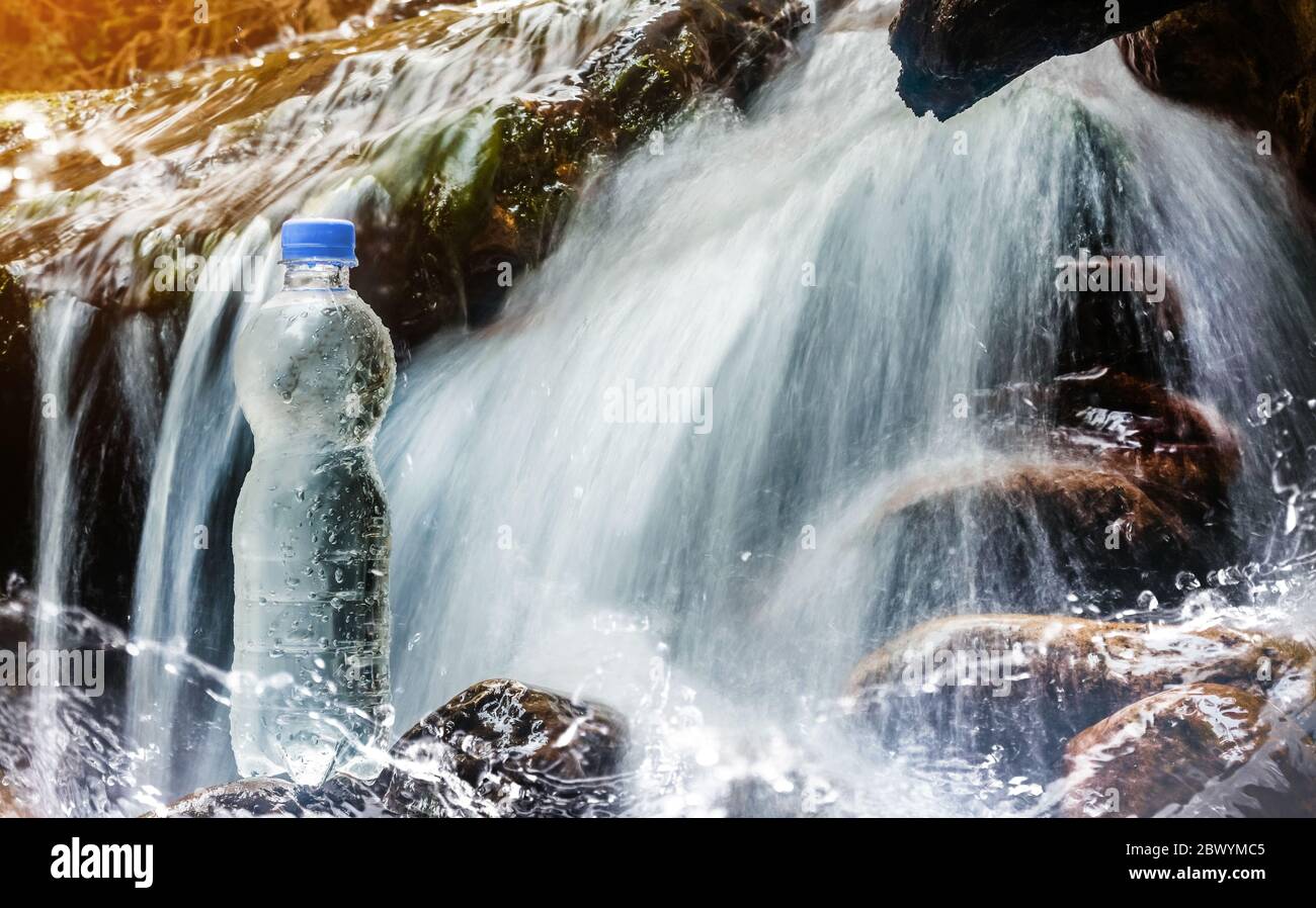 Photo of a plastic water bottle standing near streaming waterfall ...