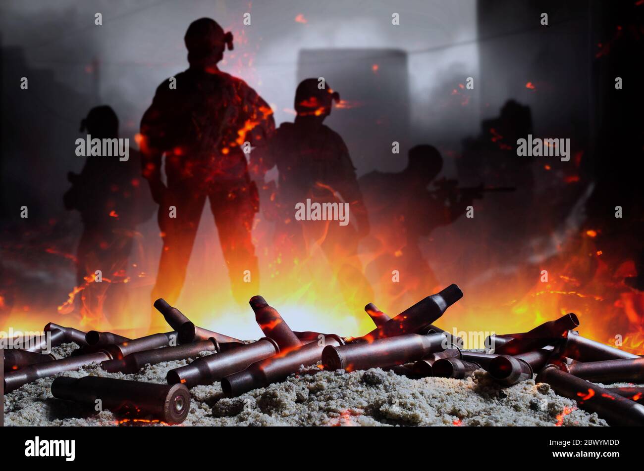 Photo of automatic rifle gun shells laying on sand with fire and ...