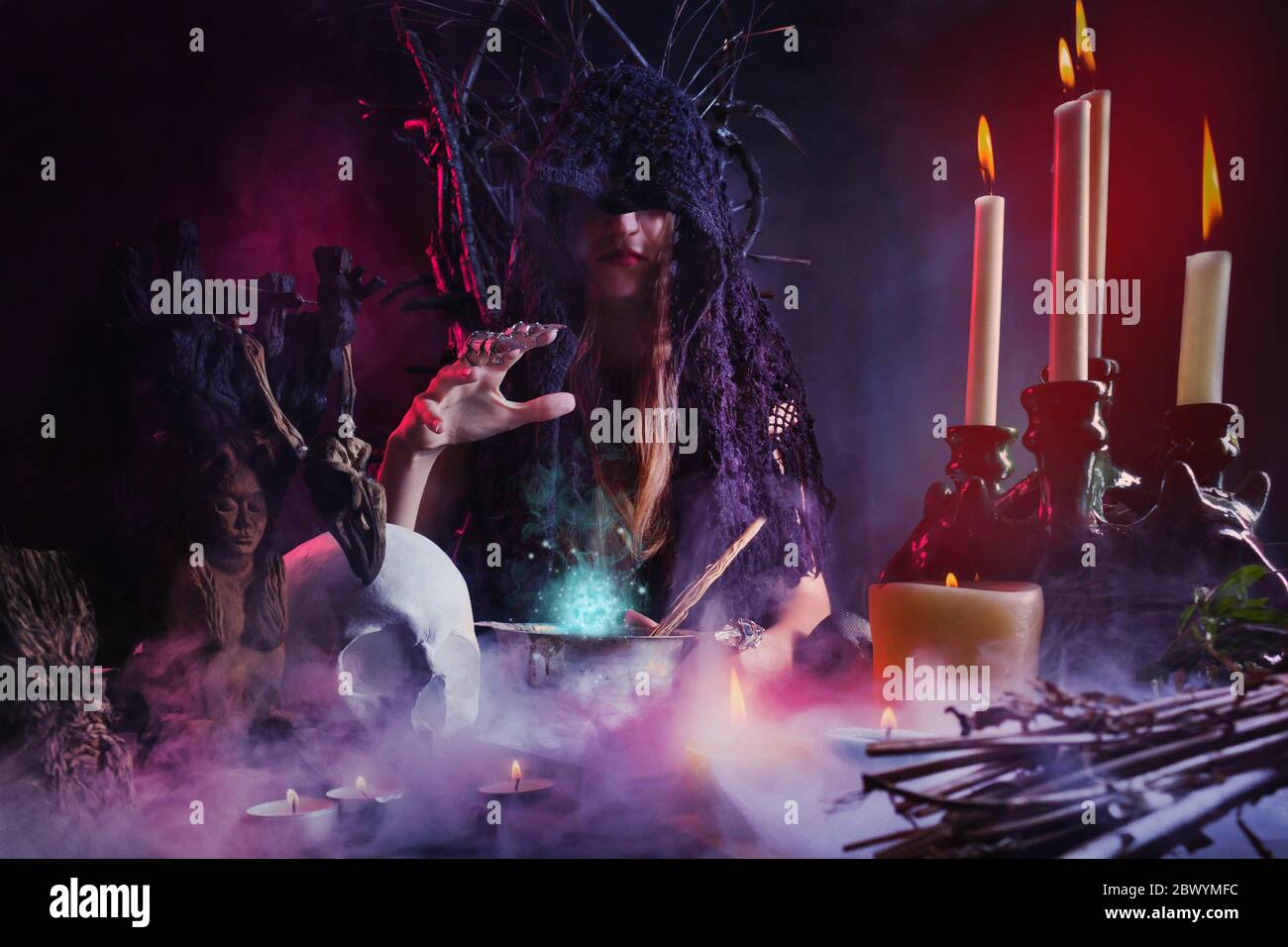 Photo of a female witch sitting at a table full of magic amulets, books ...