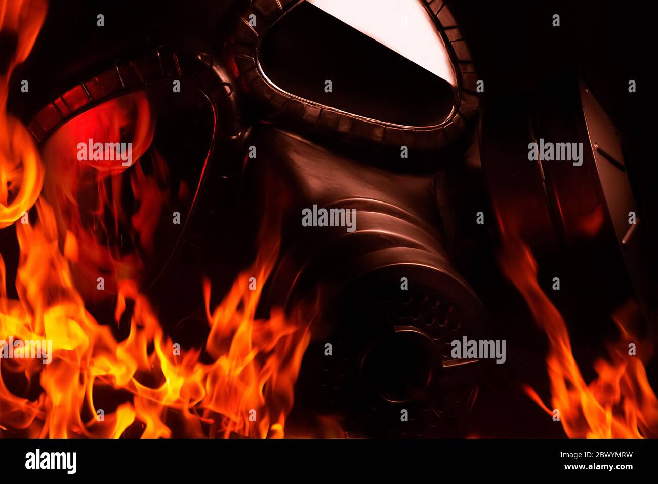 Photo of a black burning military gas mask laying in flames on black ...