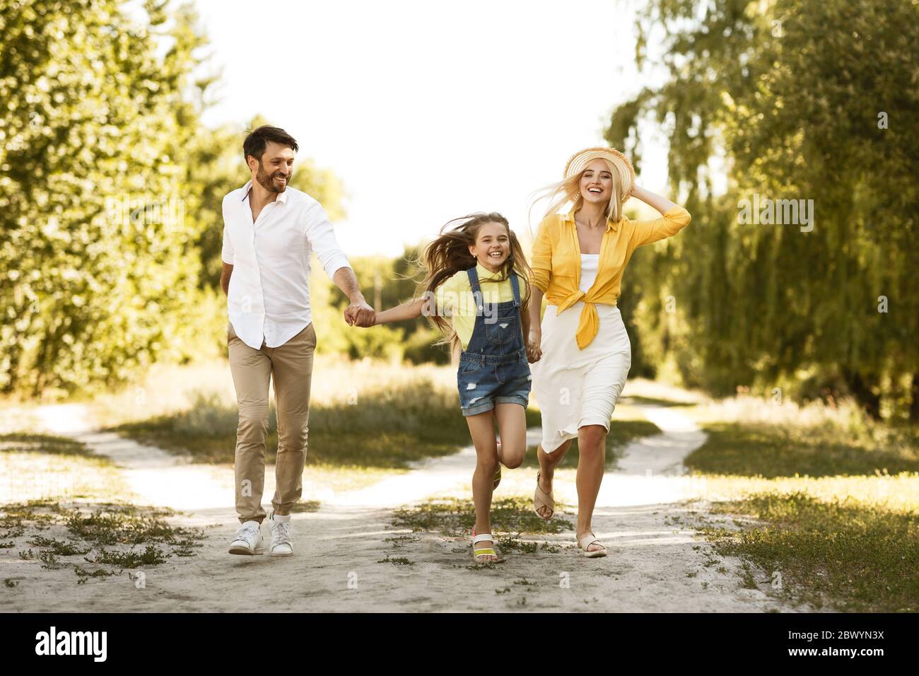 Happy Family Of Three Running Enjoying Outdoor Walk In Countryside ...