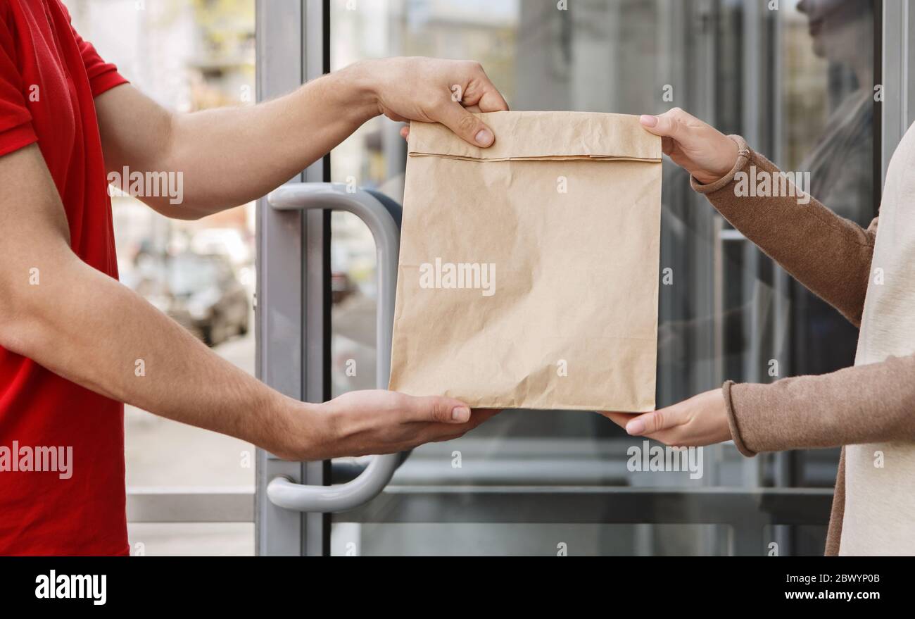 Transfer of parcel on doorstep of house. Courier and girl hold paper ...