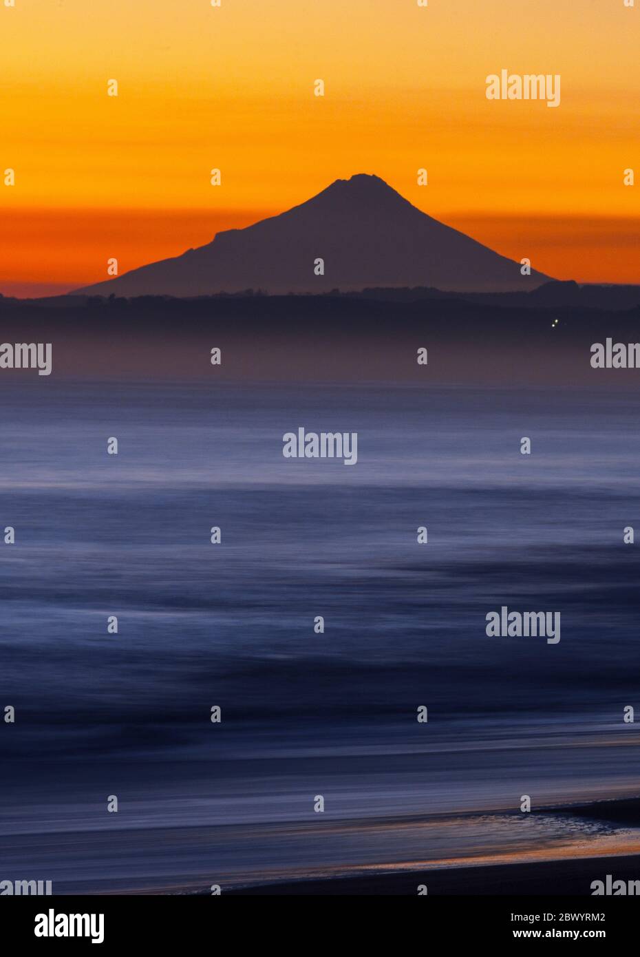 A portrait view of New Zealand's Mt Taranaki at sunset, with a time ...