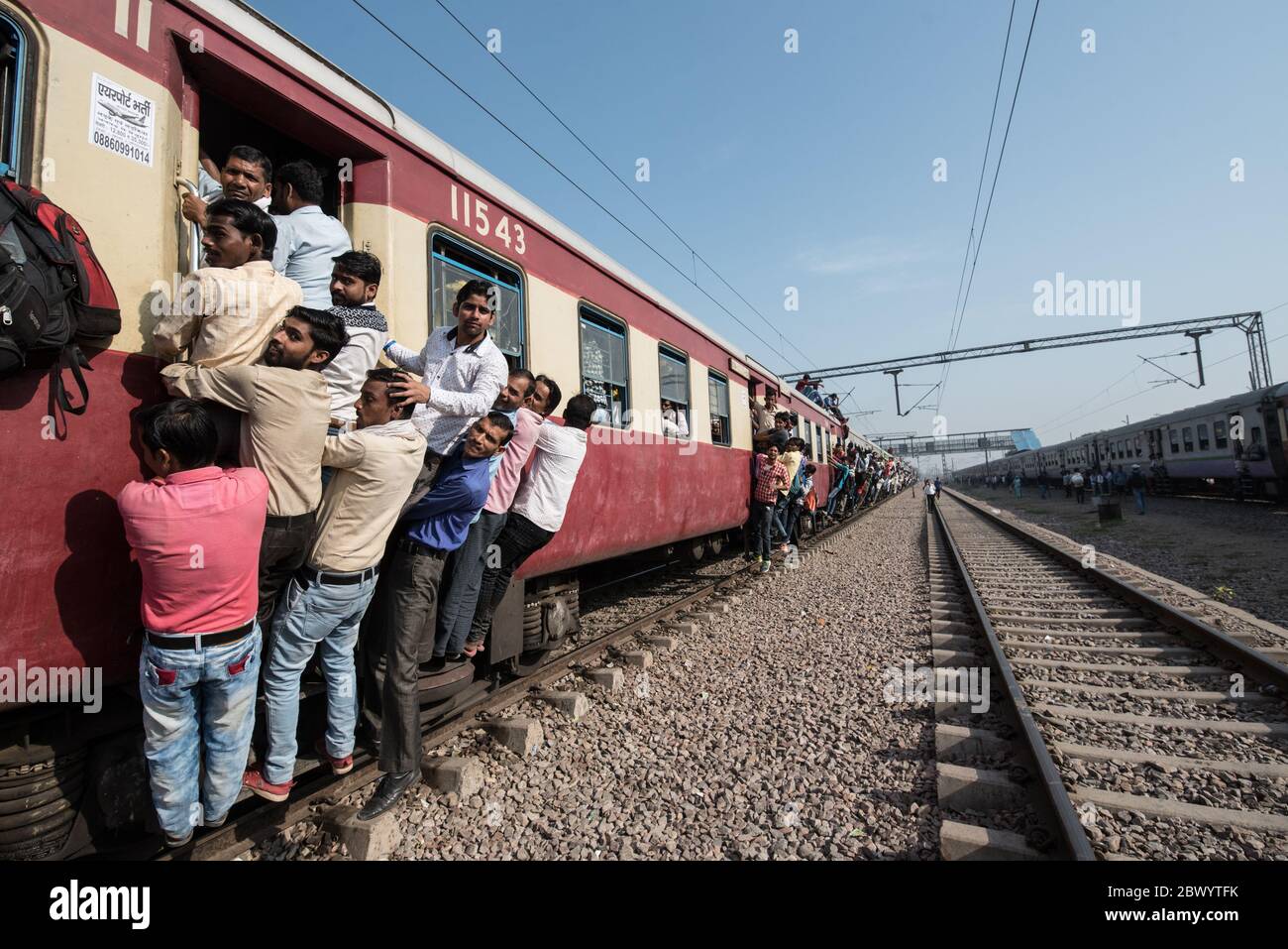 Commuters hang out of an overcrowded Indian Railways train, at Noli ...