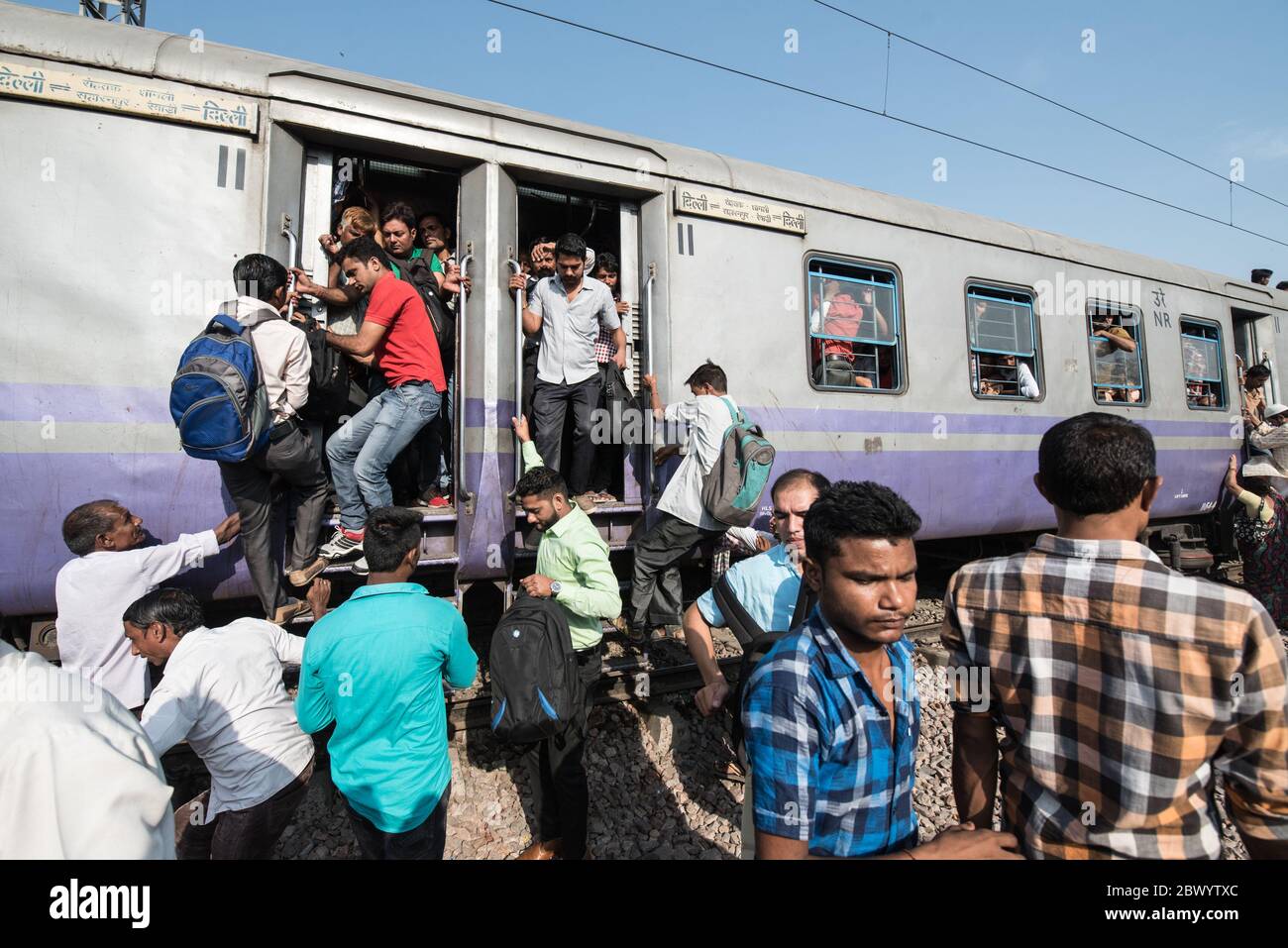 Commuters hang out of an overcrowded Indian Railways train, at Noli ...
