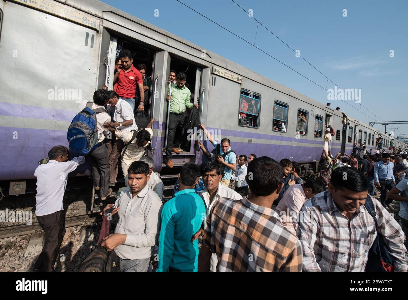 Commuters hang out of an overcrowded Indian Railways train, at Noli ...