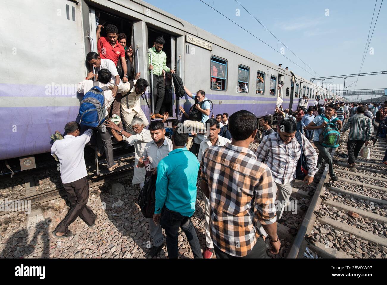 Commuters hang out of an overcrowded Indian Railways train, at Noli ...
