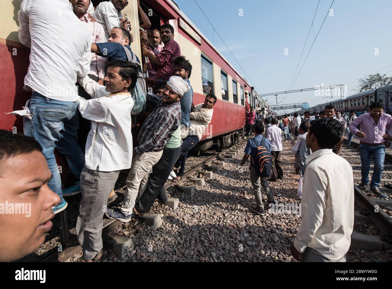 Commuters hang out of an overcrowded Indian Railways train, at Noli ...