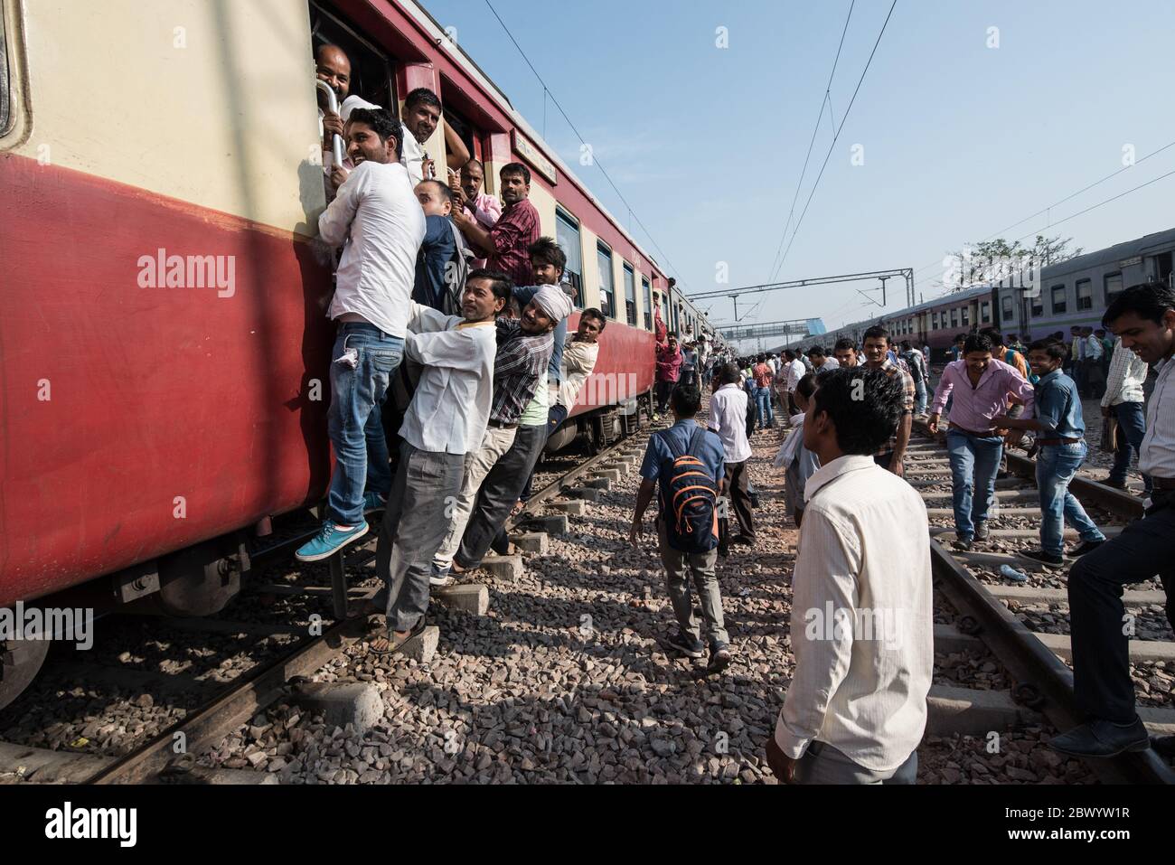 Commuters hang out of an overcrowded Indian Railways train, at Noli ...