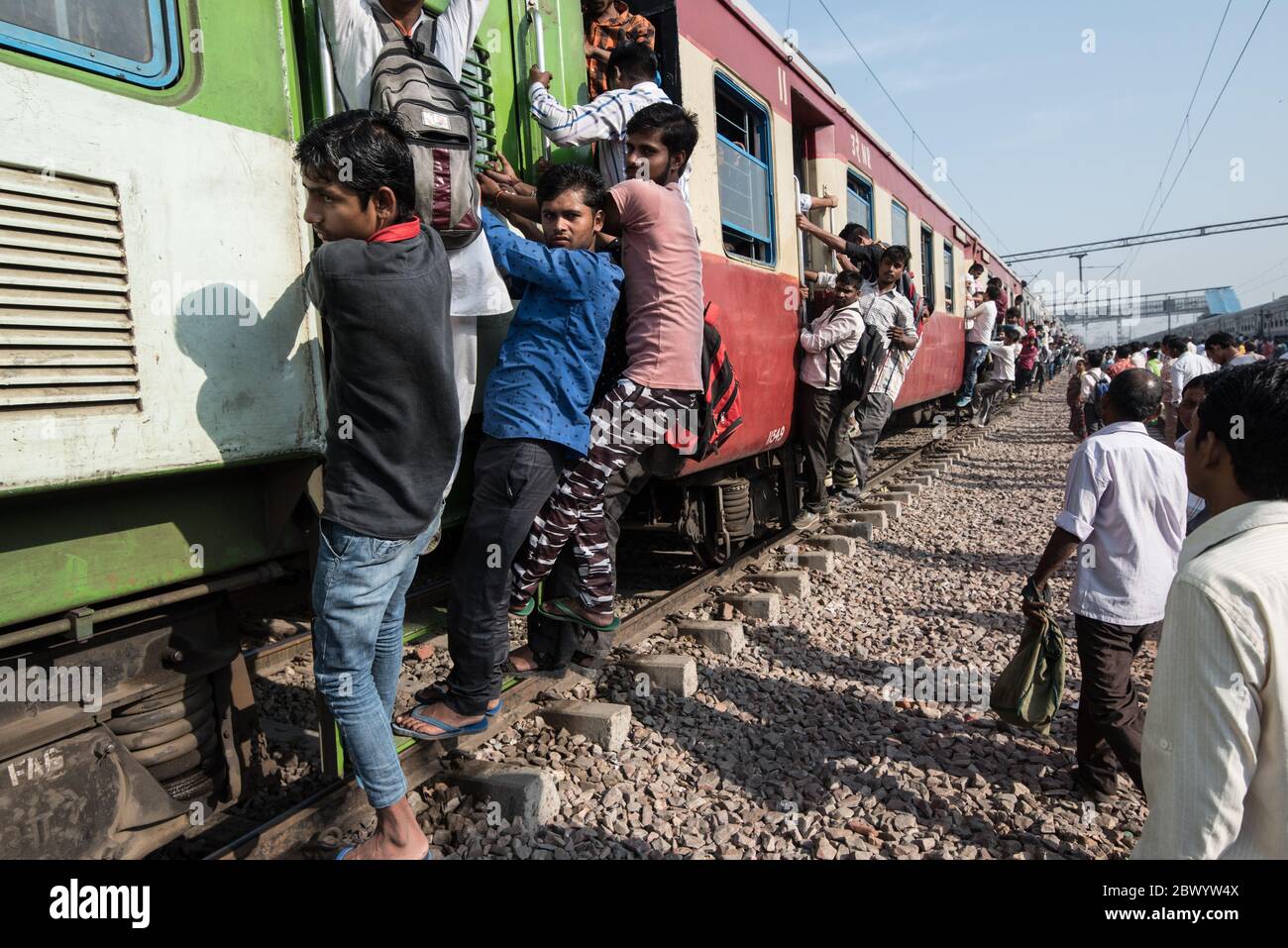Commuters hang out of an overcrowded Indian Railways train, at Noli ...