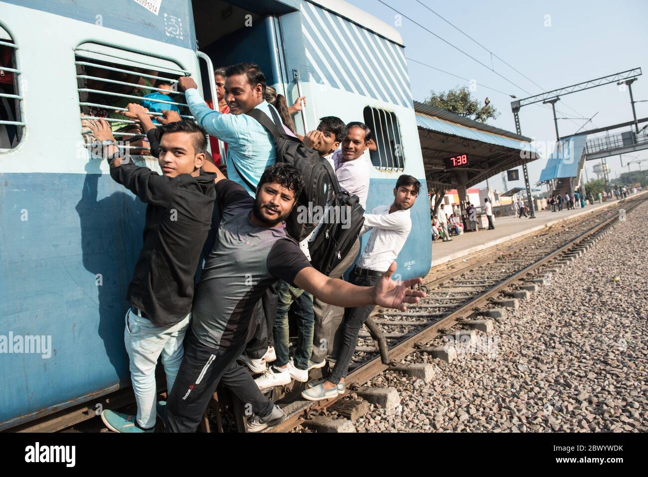 Commuters hang out of an overcrowded Indian Railways train, at Noli ...
