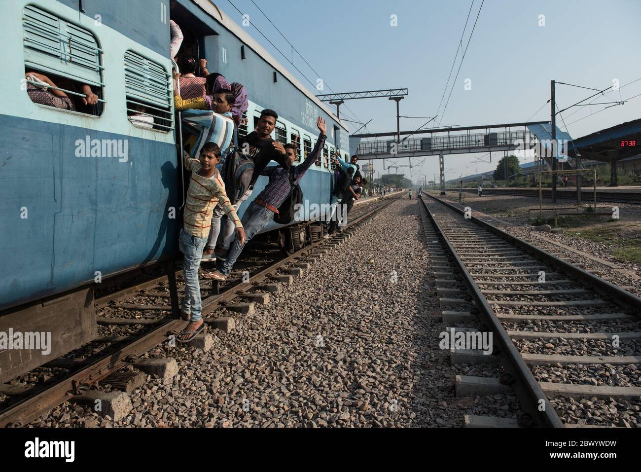 Commuters hang out of an overcrowded Indian Railways train, at Noli ...