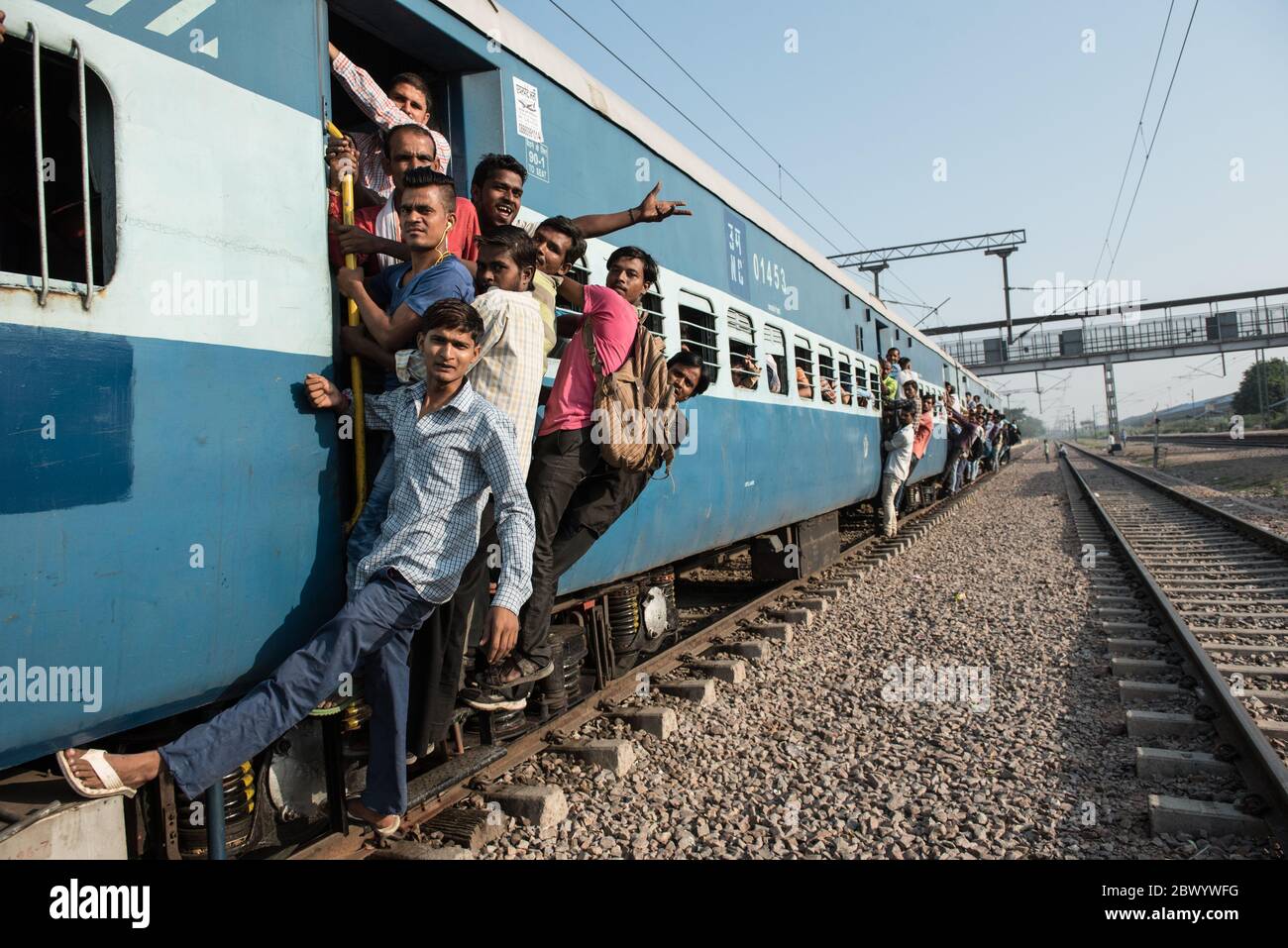 Commuters hang out of an overcrowded Indian Railways train, at Noli ...