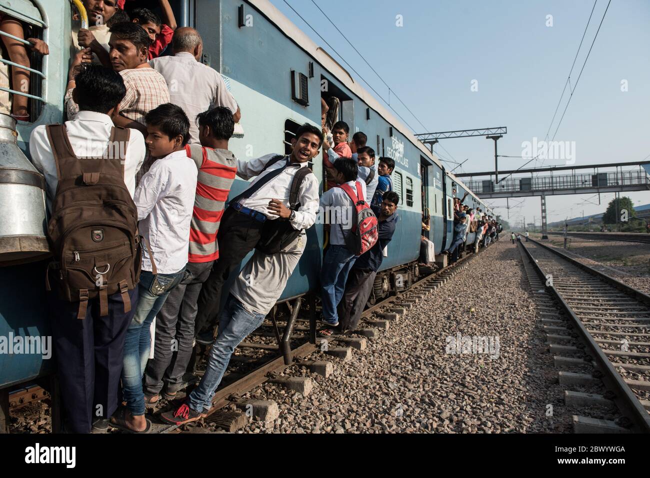 Commuters hang out of an overcrowded Indian Railways train, at Noli ...