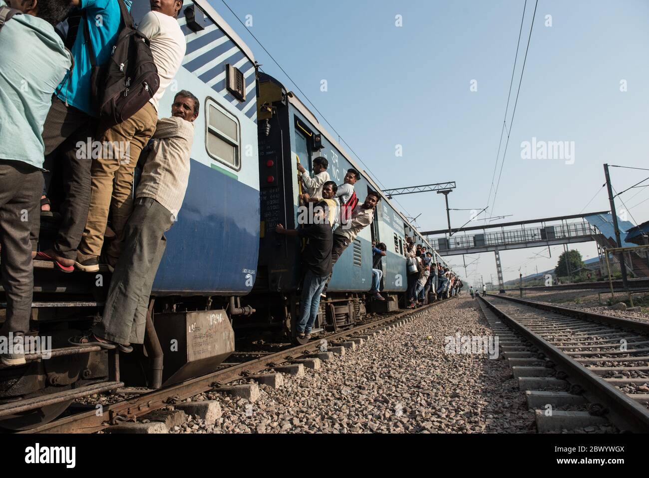 Commuters hang out of an overcrowded Indian Railways train, at Noli ...