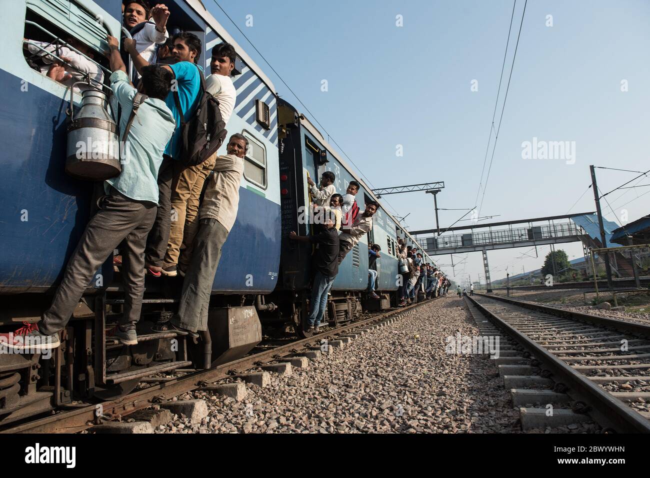 Commuters hang out of an overcrowded Indian Railways train, at Noli ...