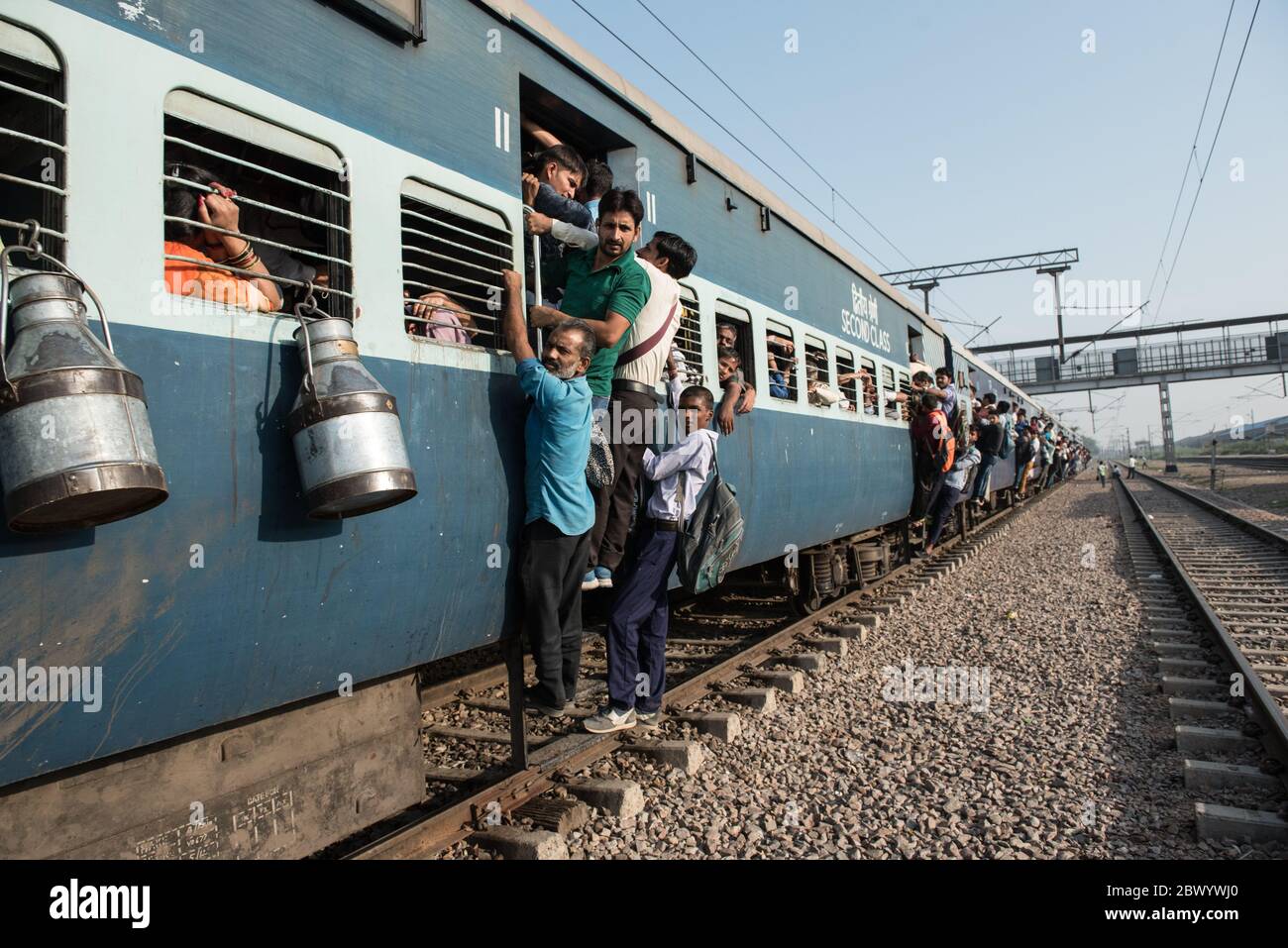 Commuters hang out of an overcrowded Indian Railways train, at Noli ...